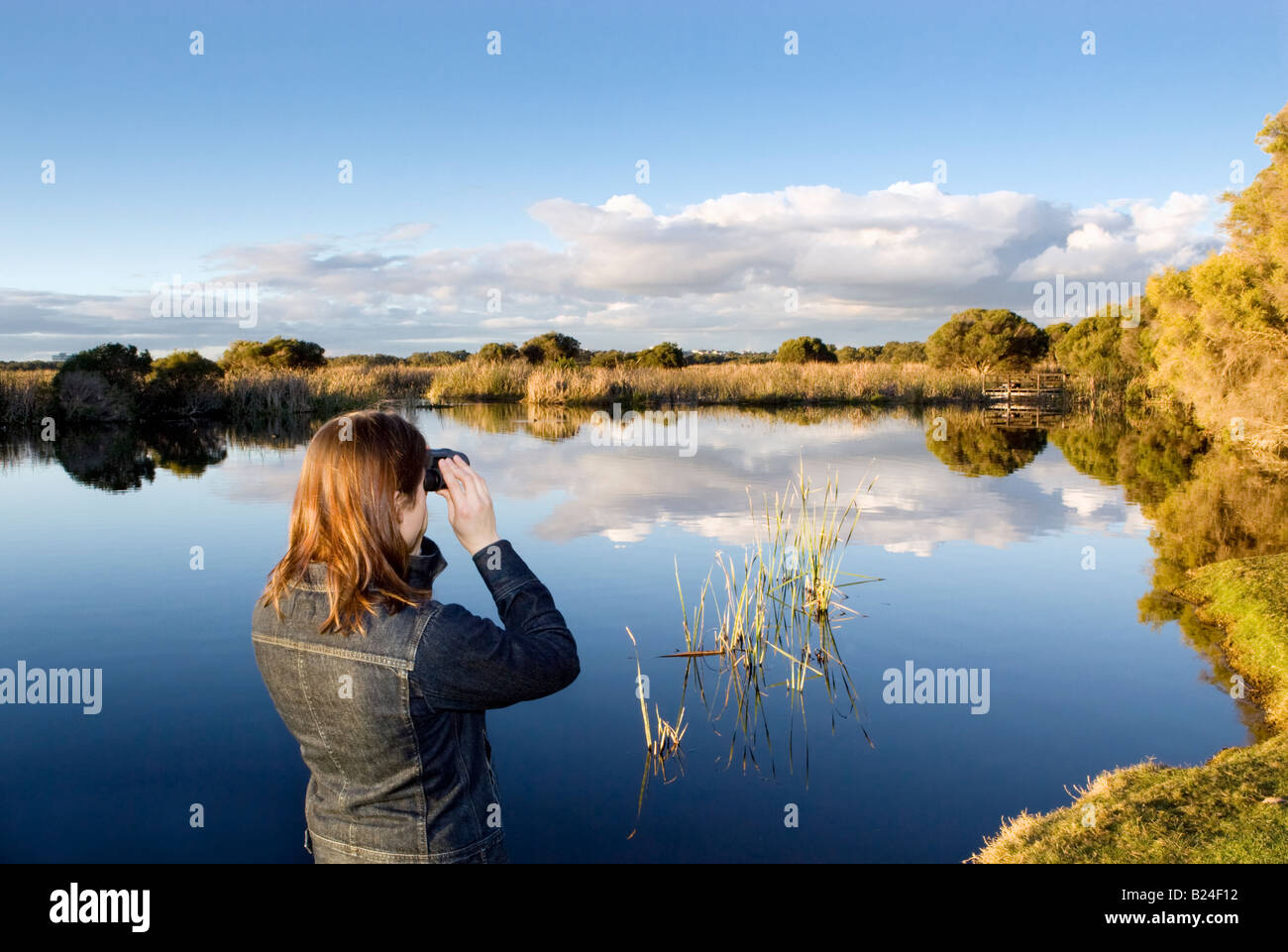 A woman with binoculars birdwatching at the side of a lake Stock Photo ...