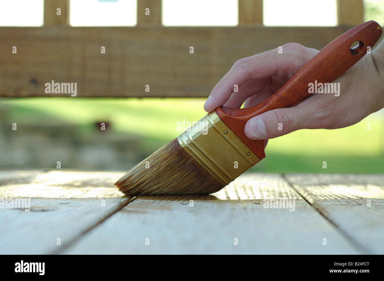 Man holding a brush while staining cedar deck floor Stock Photo - Alamy