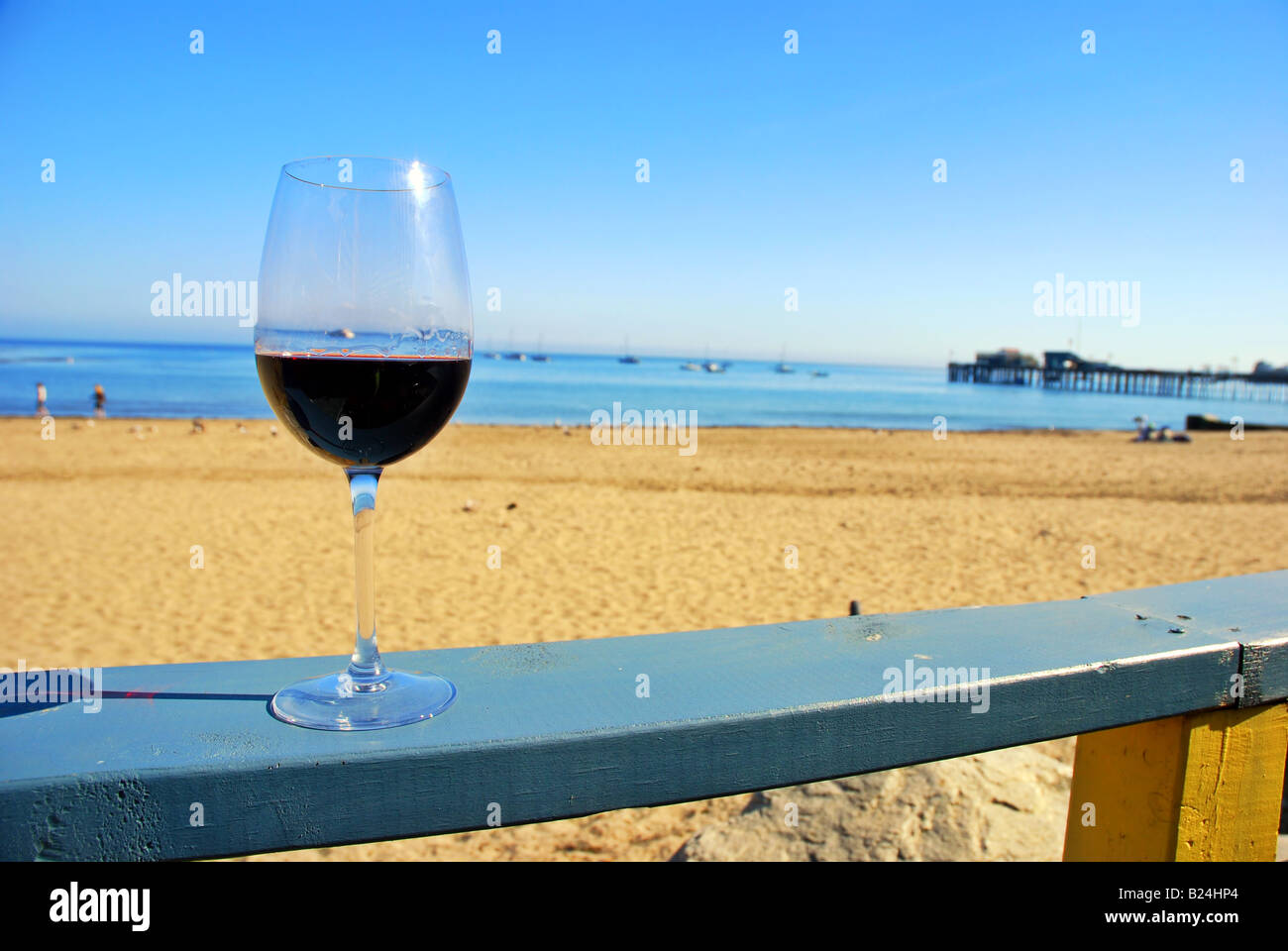 Glass of red wine on a restaurant s deck railing by the ocean beach ...