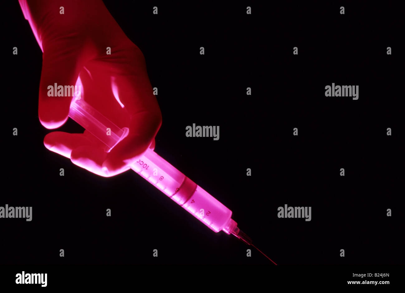 GLOVED HAND HOLDING SYRINGE DRAMATIC LIGHTING Stock Photo - Alamy