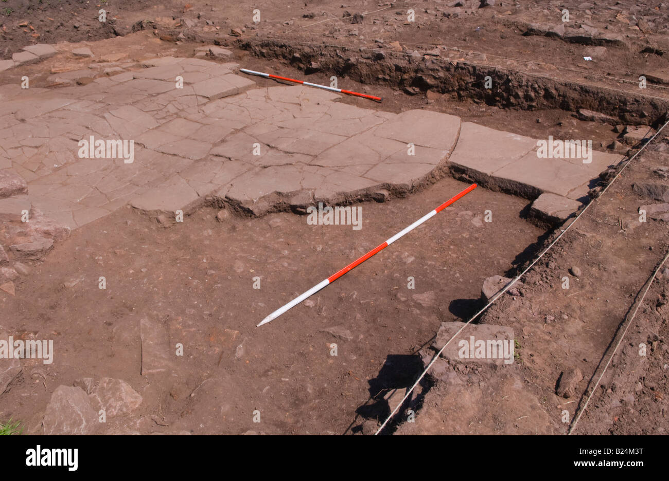 Flag stone floor with measuring poles at excavation of warehouse of ...