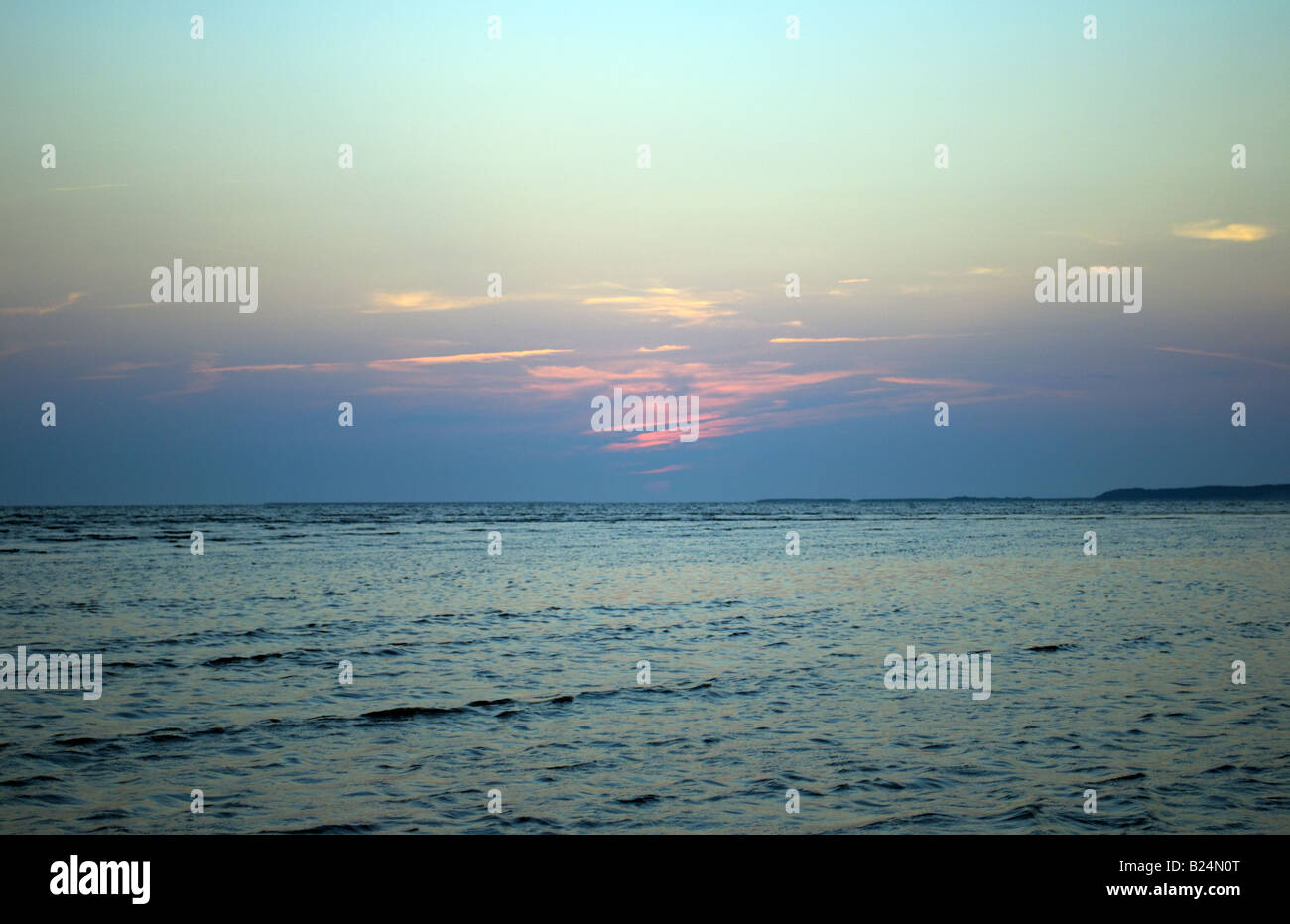 sun setting above the water with reflections in water Stock Photo - Alamy