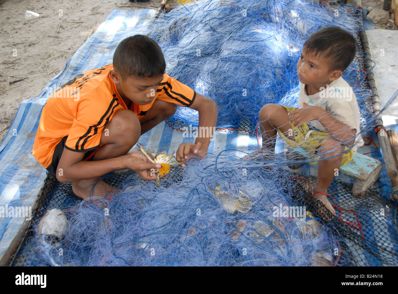 boys cleaning nets of fish and crabs , pig island(koh sukorn) , trang ...