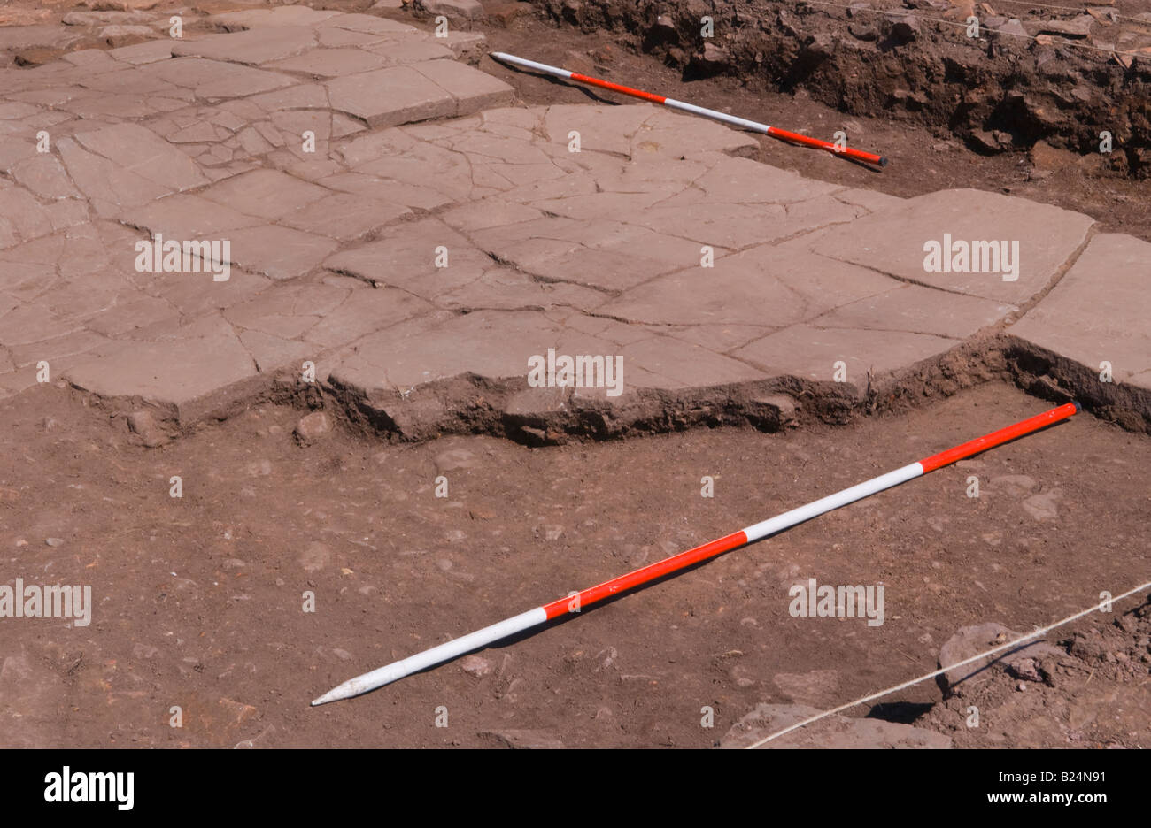 Flag stone floor with measuring poles at excavation of warehouse of ...