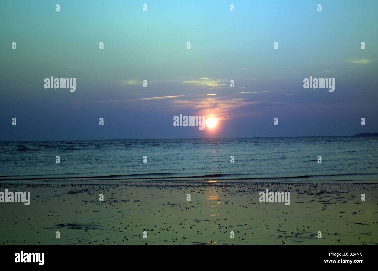 sun setting above the water with reflections in water Stock Photo - Alamy