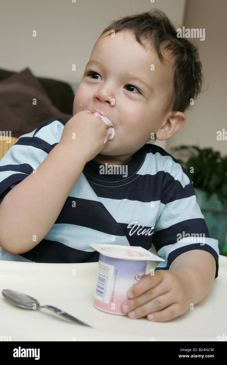 Toddler using his hands to eat yoghurt Stock Photo - Alamy