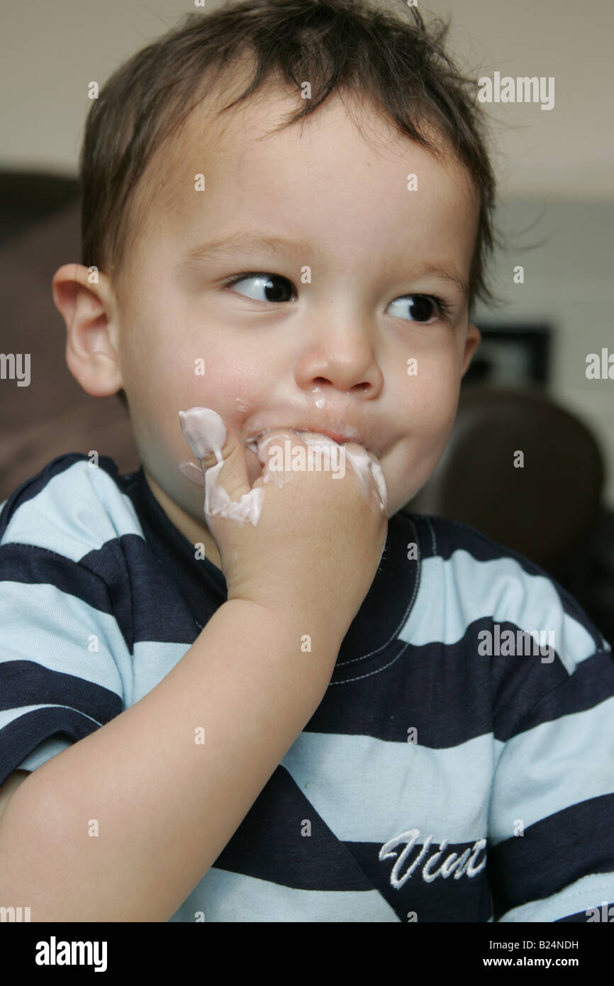 Child eating yoghurt using his hands Stock Photo - Alamy