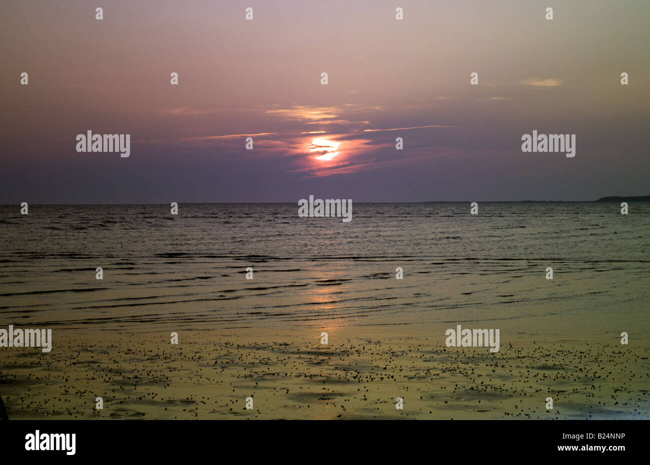 sun setting above the water with reflections in water Stock Photo - Alamy