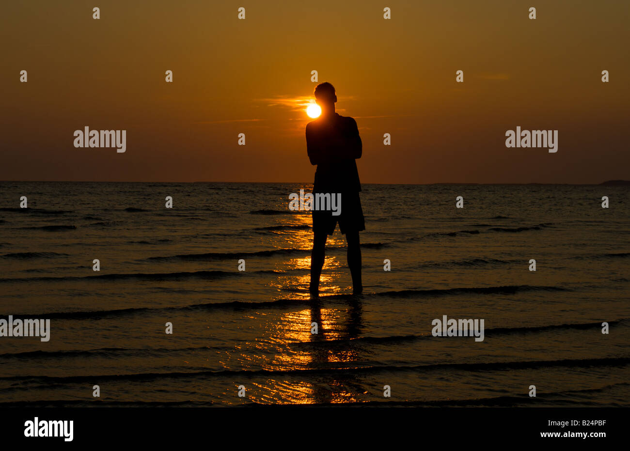 sun setting above the water with reflections in water Stock Photo - Alamy