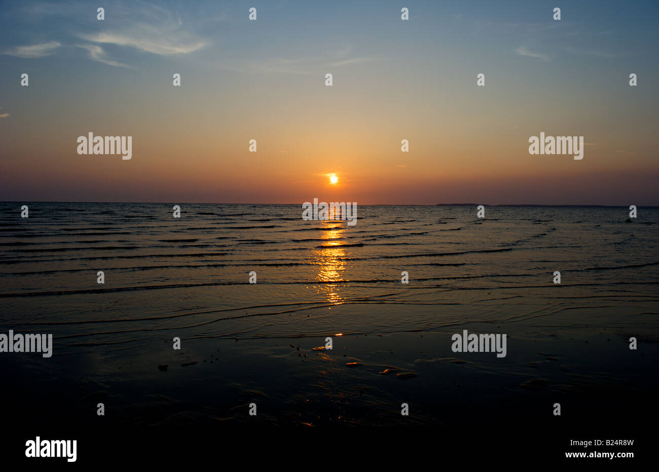 sun setting above the water with reflections in water Stock Photo - Alamy