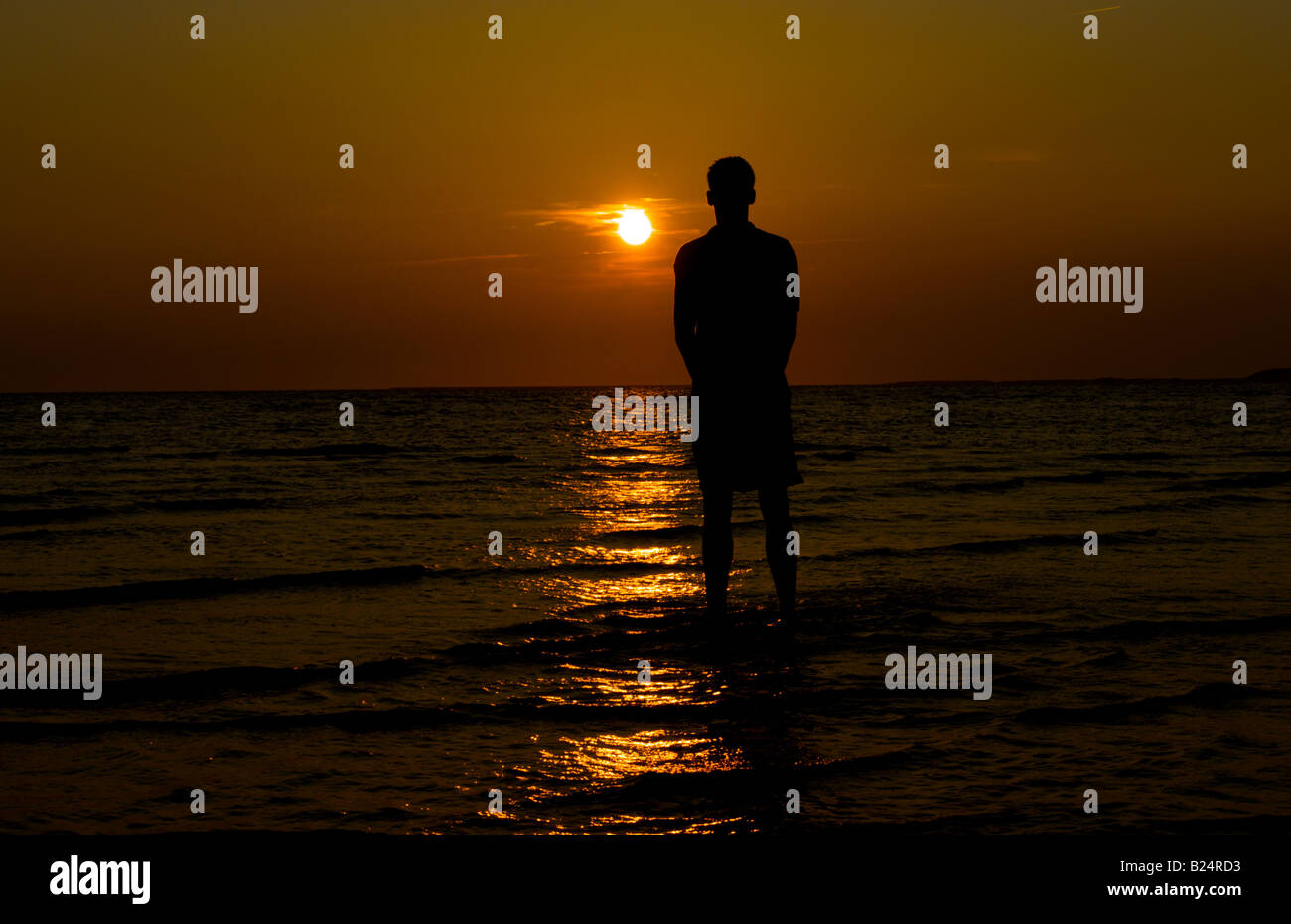 sun setting above the water with reflections in water Stock Photo - Alamy