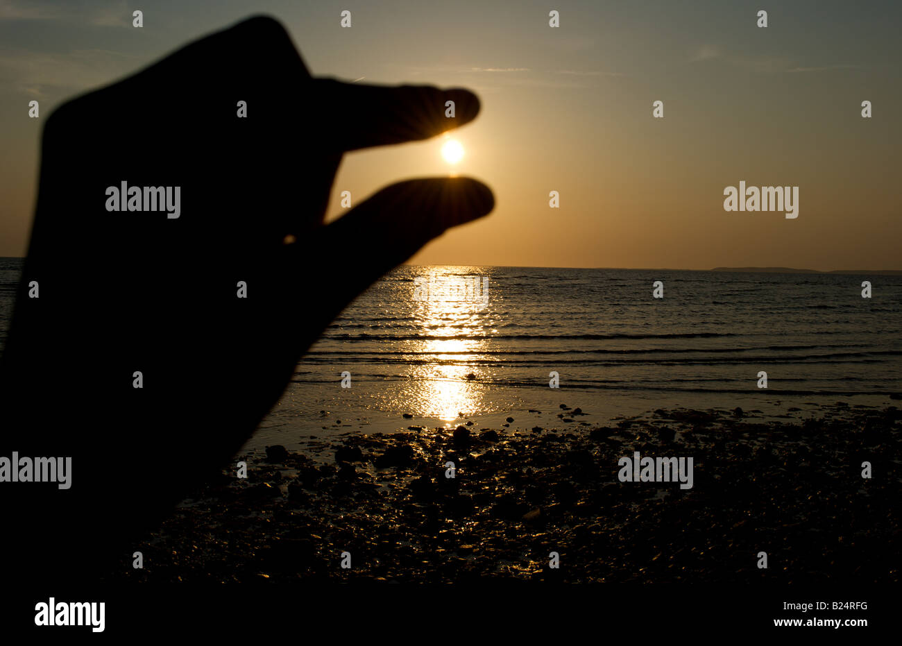 sun setting above the water with reflections in water Stock Photo - Alamy