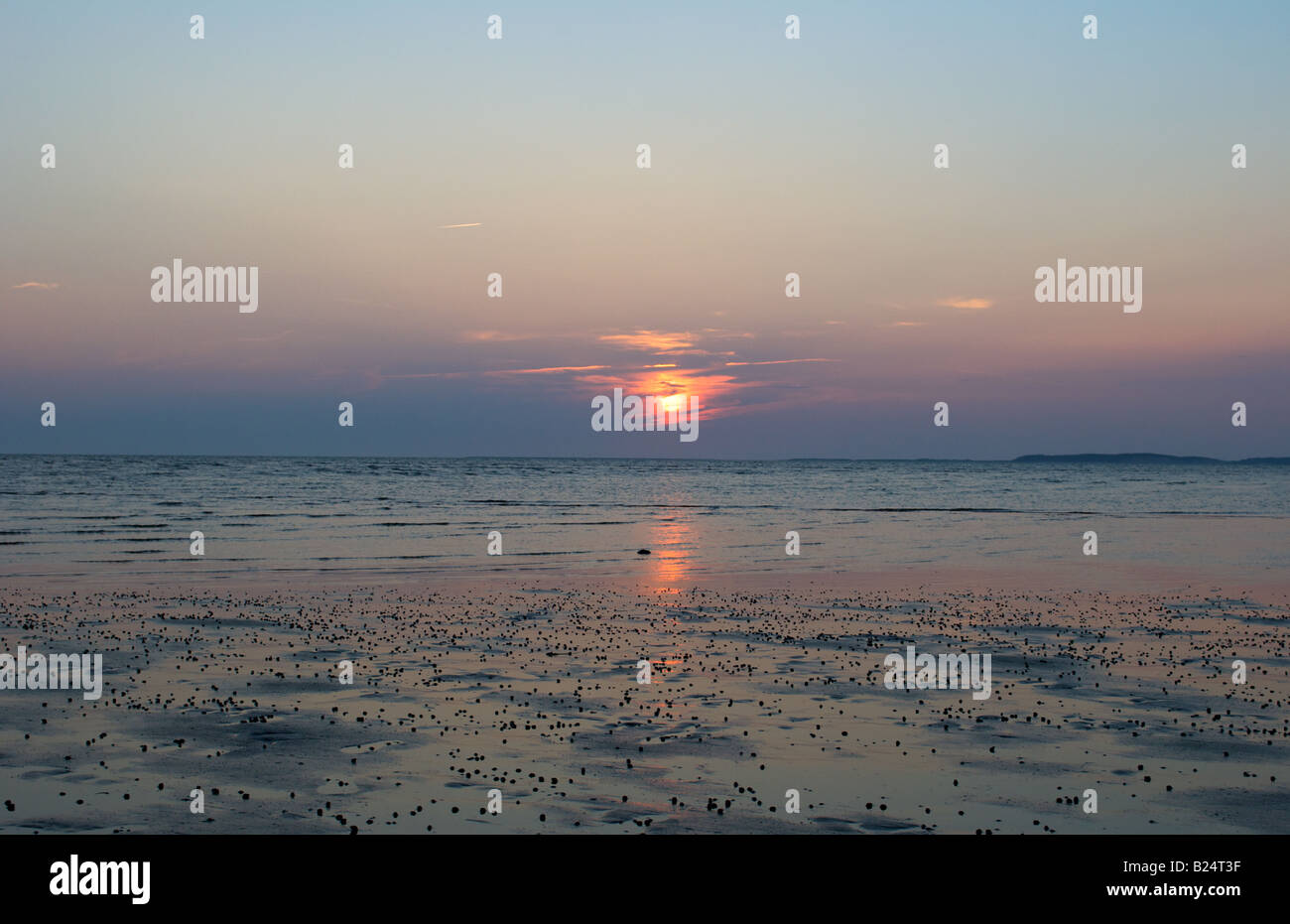 sun setting above the water with reflections in water Stock Photo - Alamy
