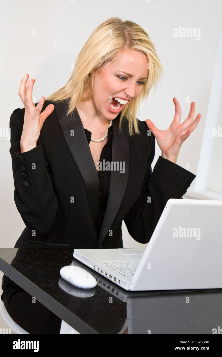 A beautiful young female executive expressing frustration at her laptop ...