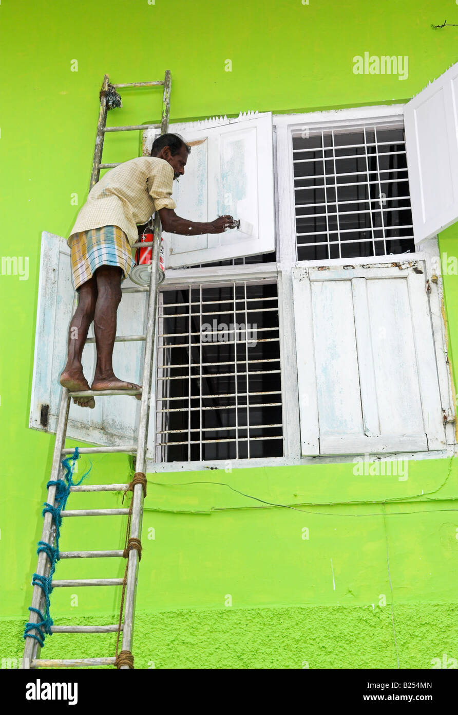 Man on top of ladder painting window shutters Stock Photo - Alamy