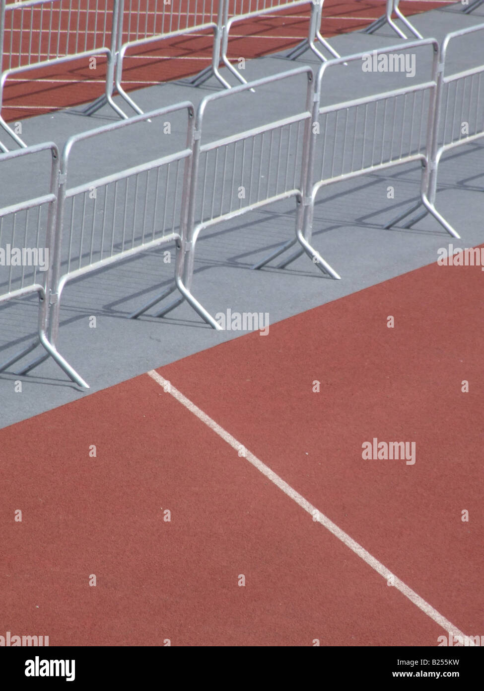 rows of many metal crowd control barriers gates on athletics track ...