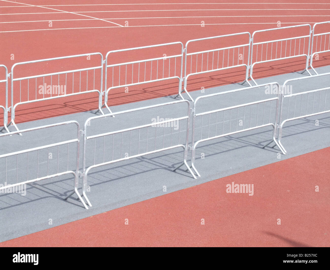 rows of many metal crowd control barriers gates on athletics track ...