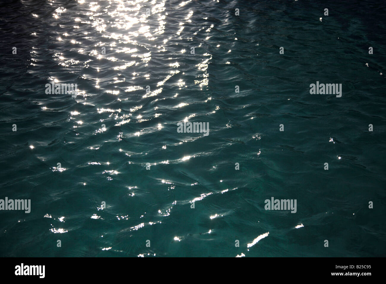 Reflection of sun setting in crystal clear blue water Stock Photo - Alamy
