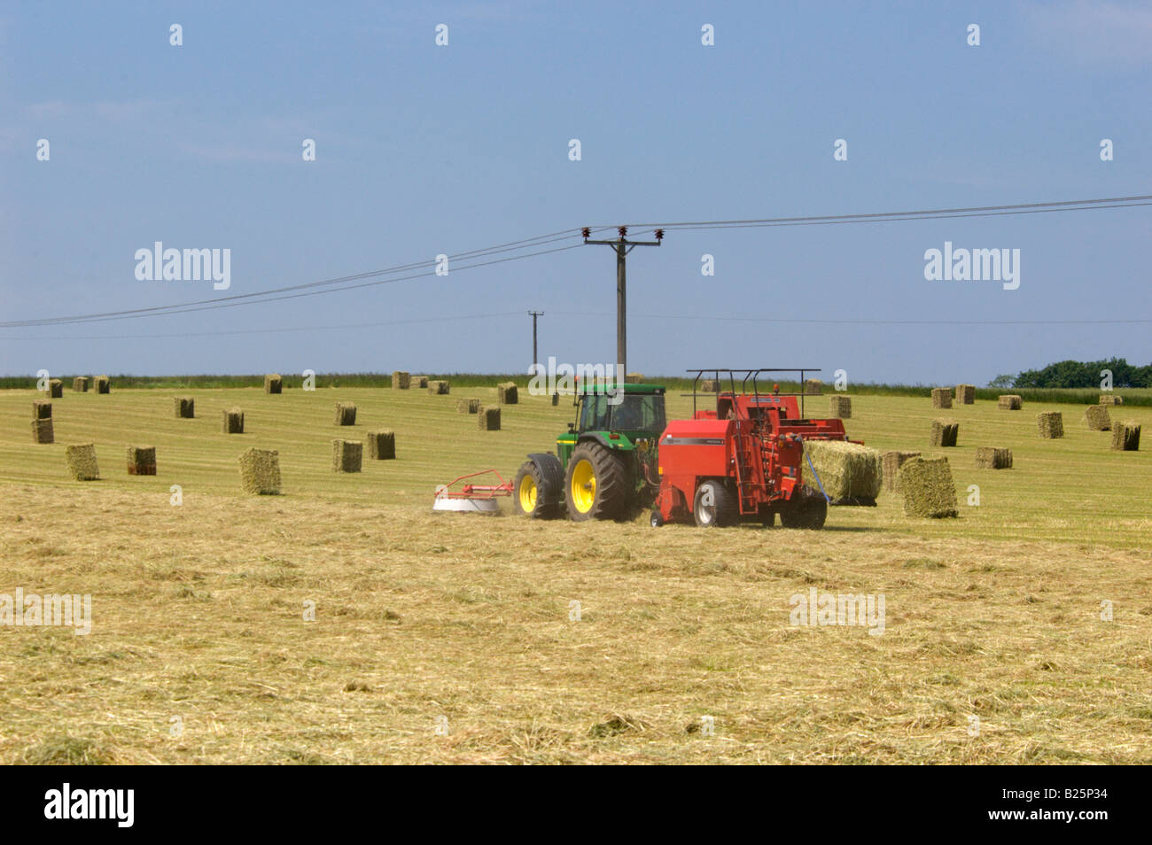 Tractor bailing hay in a field at harvest time 1/4 Stock Photo - Alamy