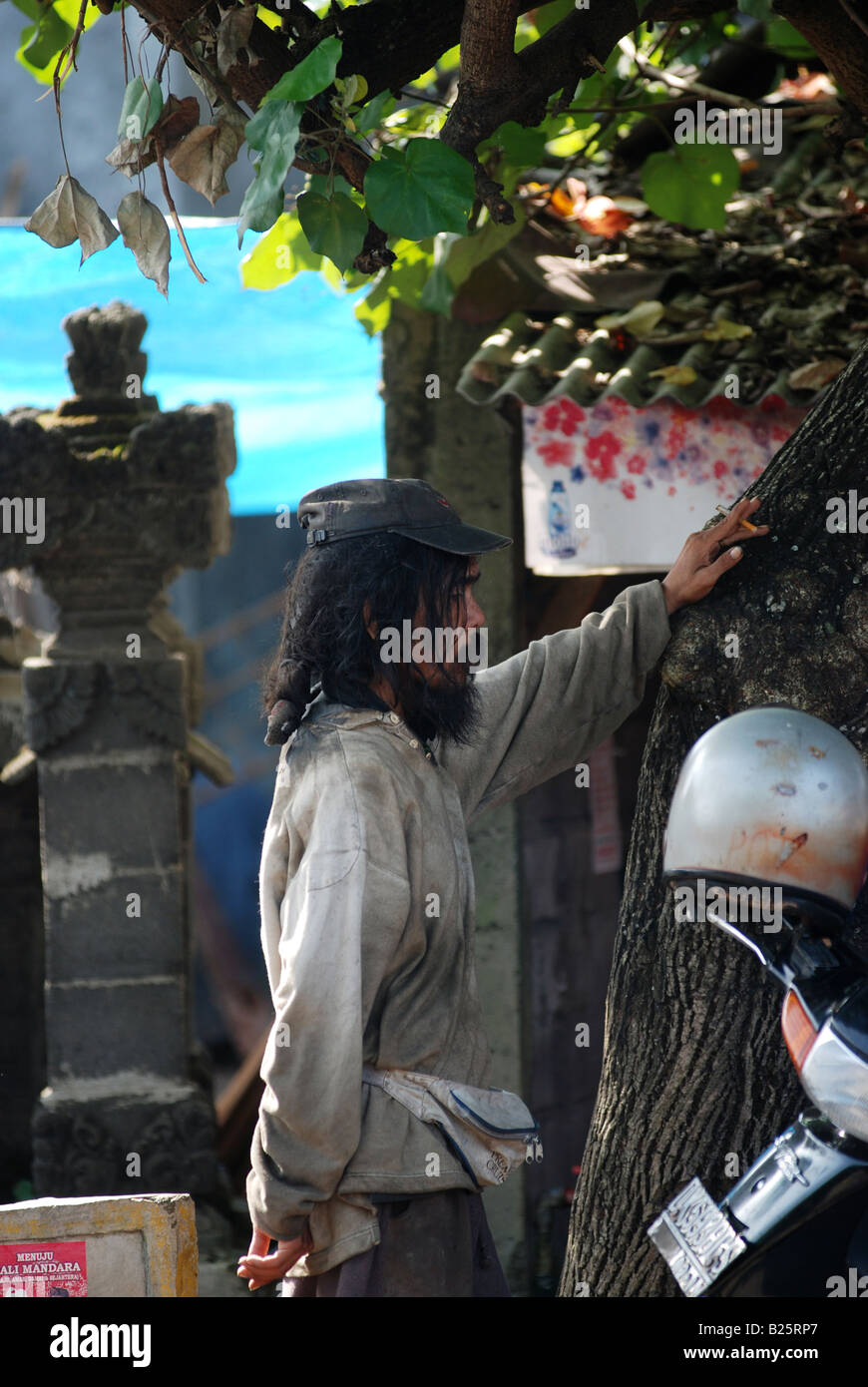 An homeless man standing under a tree in a small village west of Bali ...