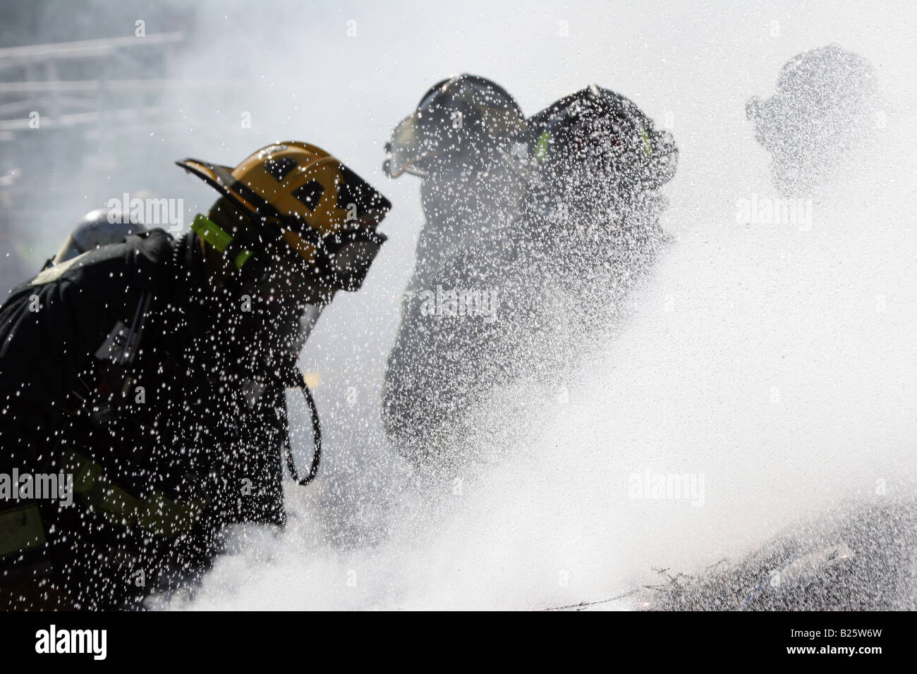Four firefighters spraying water on a car fire Stock Photo - Alamy