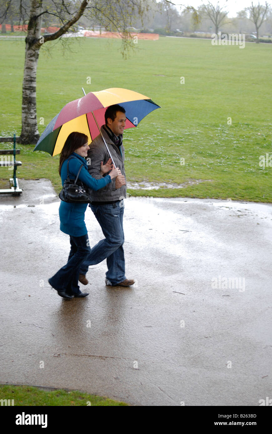 A young couple walking through a park on a wet day Stock Photo - Alamy