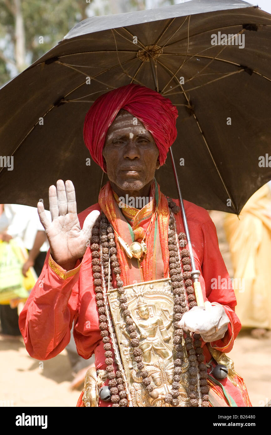 A sadhu stands under an umbrella while standing on shoes of nails at ...