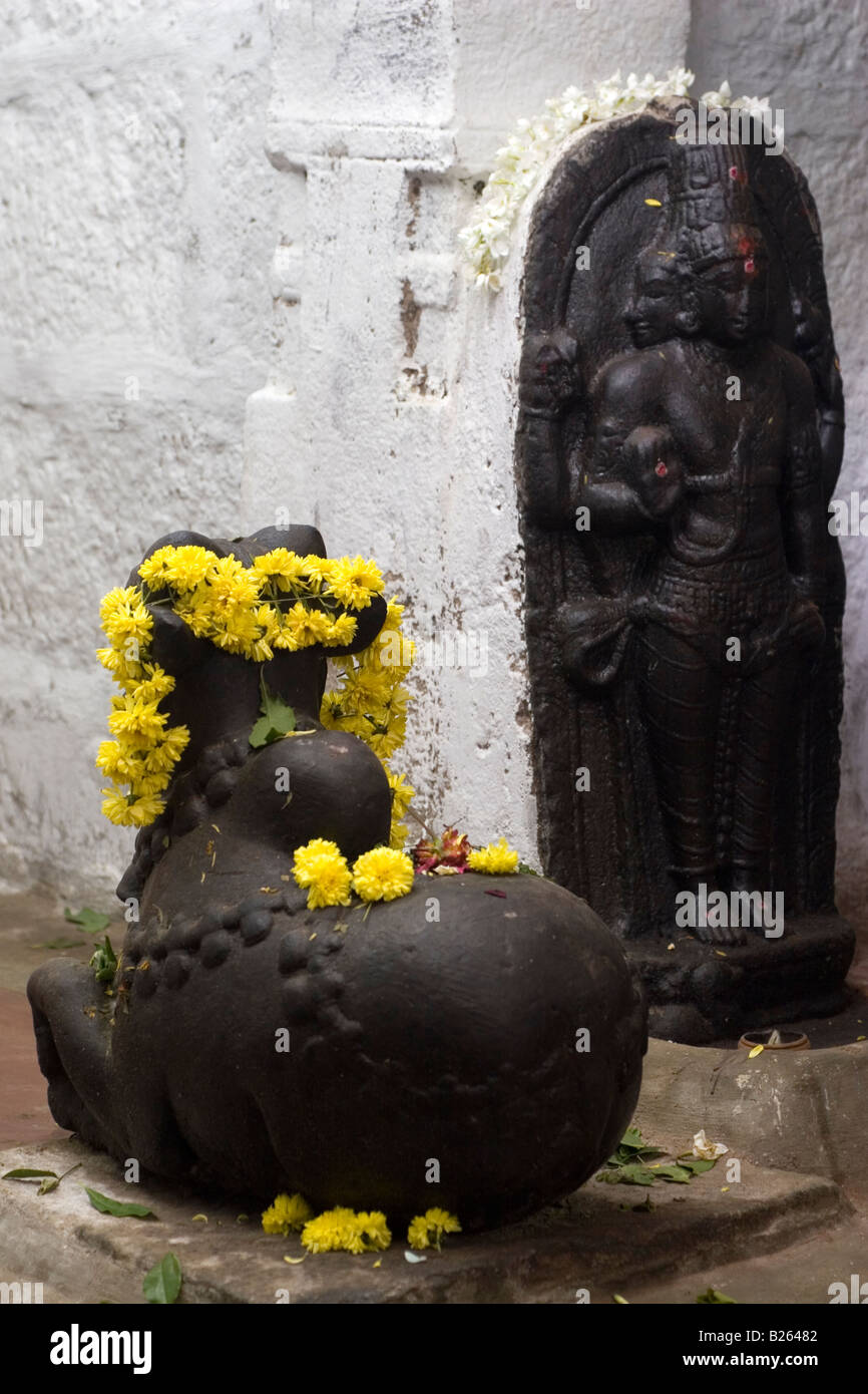 A garlanded Nandi statue and a sculpted stone statue at one of the ...