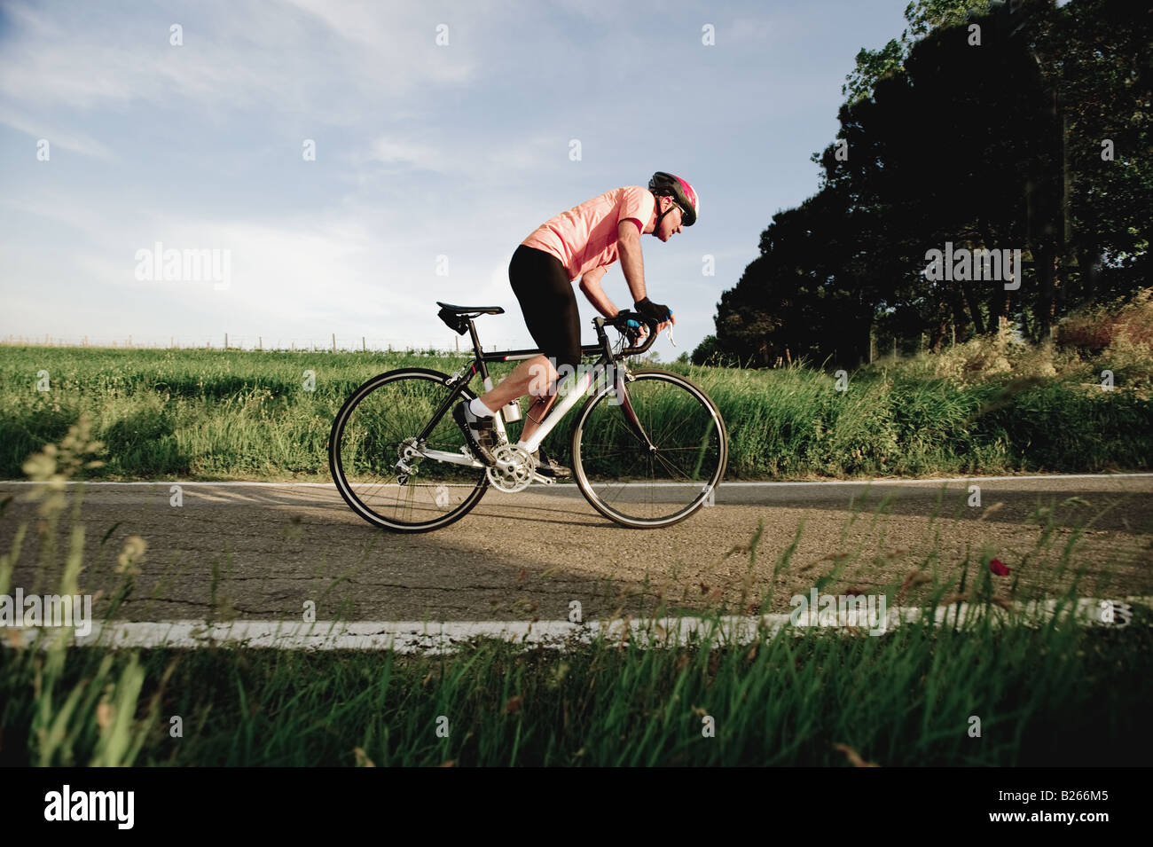 Side view of a man cycling on road Stock Photo - Alamy