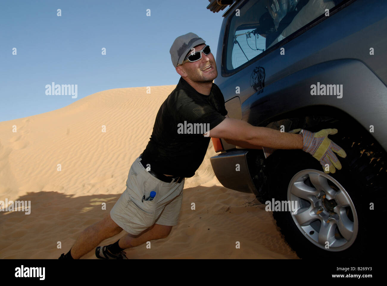 Man pushing a 4x4 vehicle, jeep out of the sand, Offroad 4x4 Sahara ...