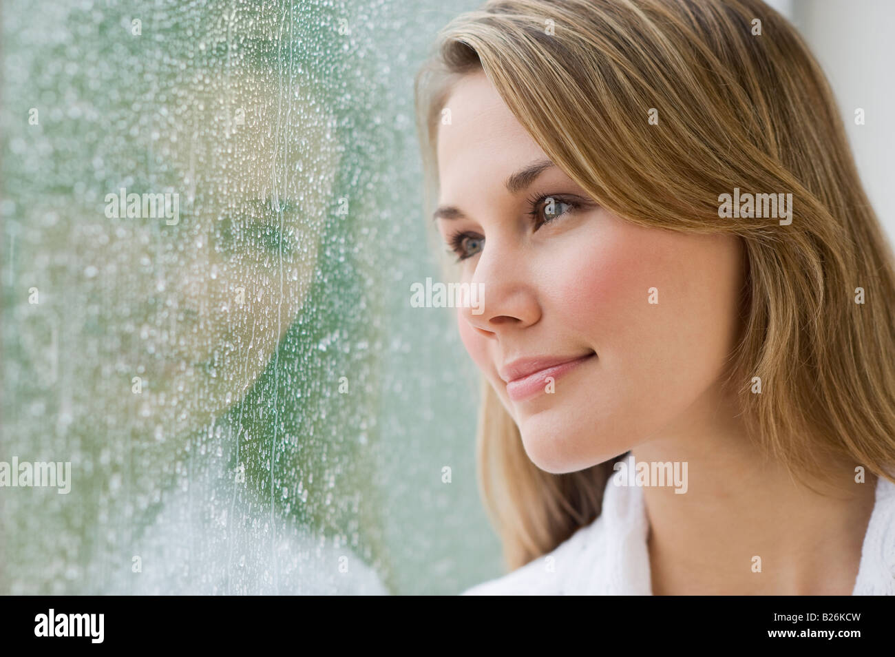 Woman looking out rainy window Stock Photo - Alamy