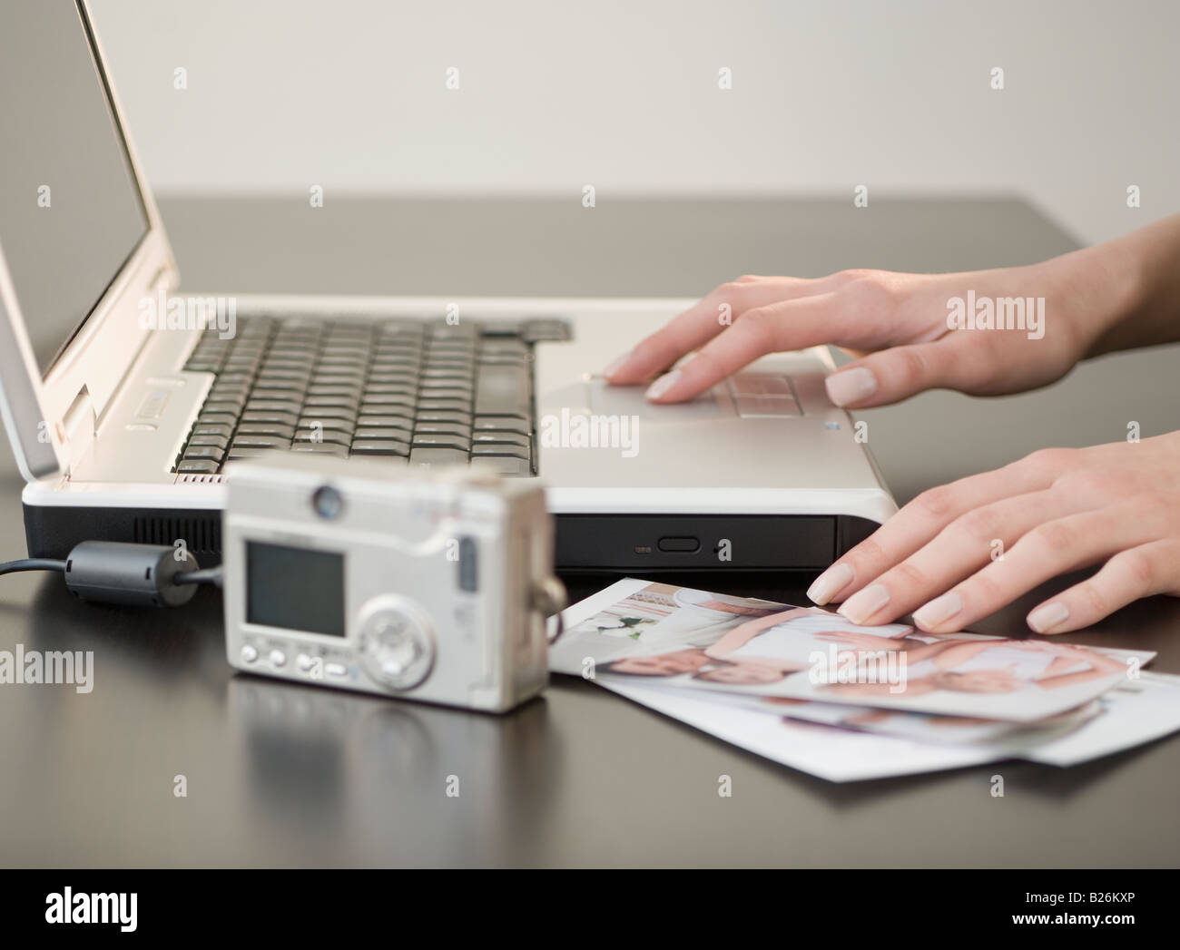 Digital camera and photographs next to laptop Stock Photo - Alamy