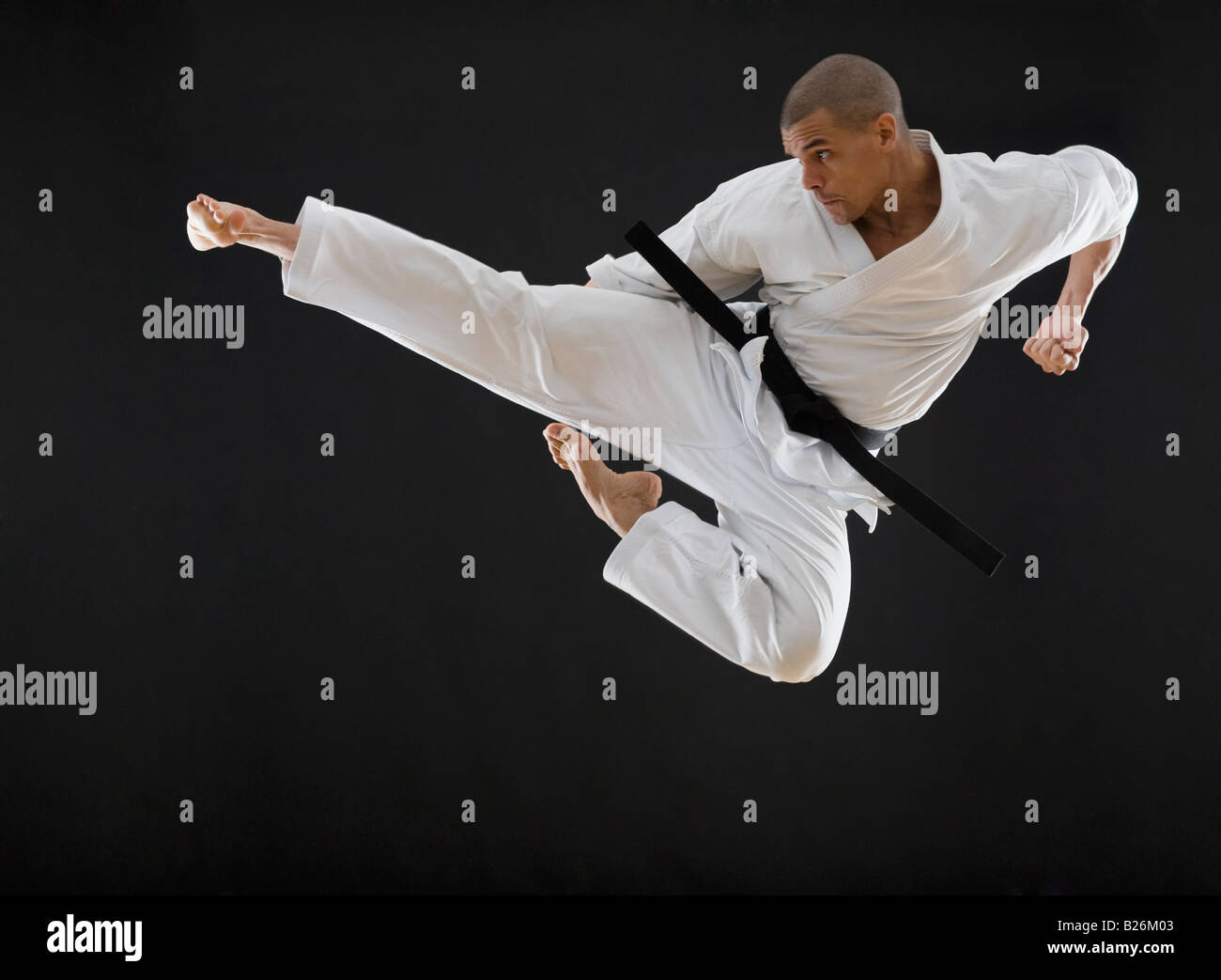Hispanic male karate black belt kicking in air Stock Photo - Alamy
