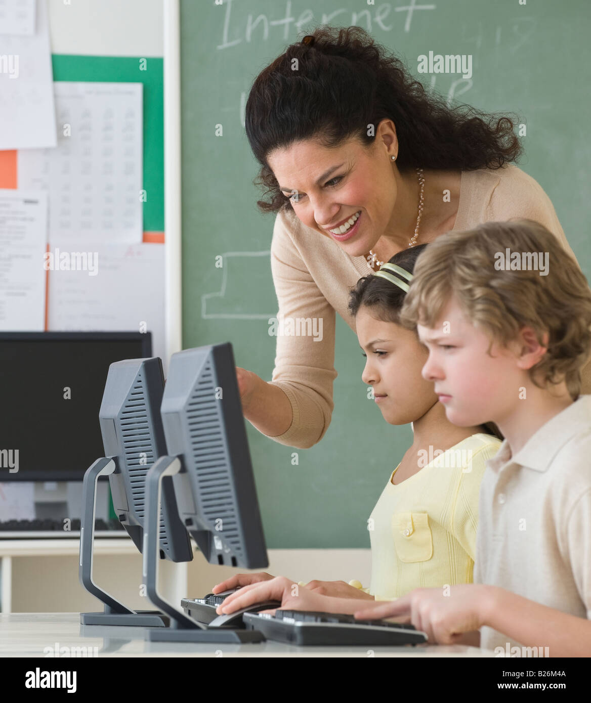Hispanic teacher helping students with computers Stock Photo - Alamy