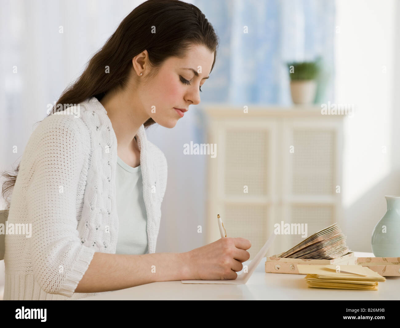 Woman writing at table Stock Photo - Alamy