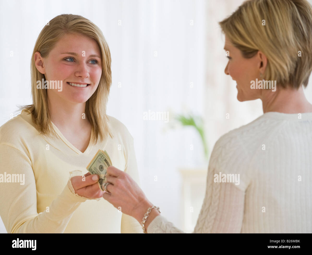 Mother giving money to teenaged daughter Stock Photo - Alamy