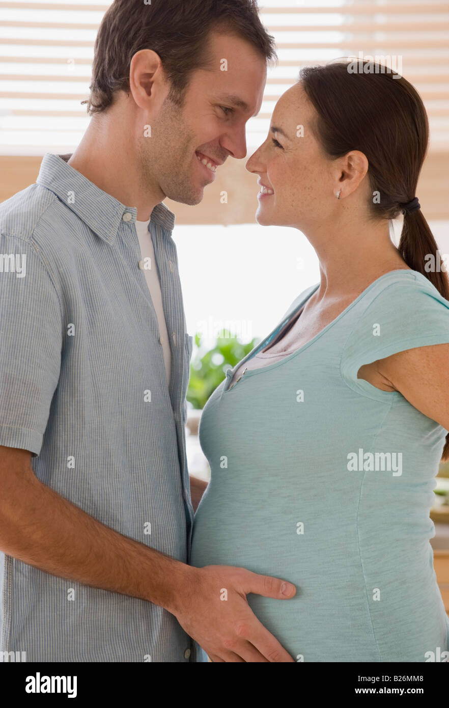 Pregnant Hispanic couple hugging Stock Photo - Alamy