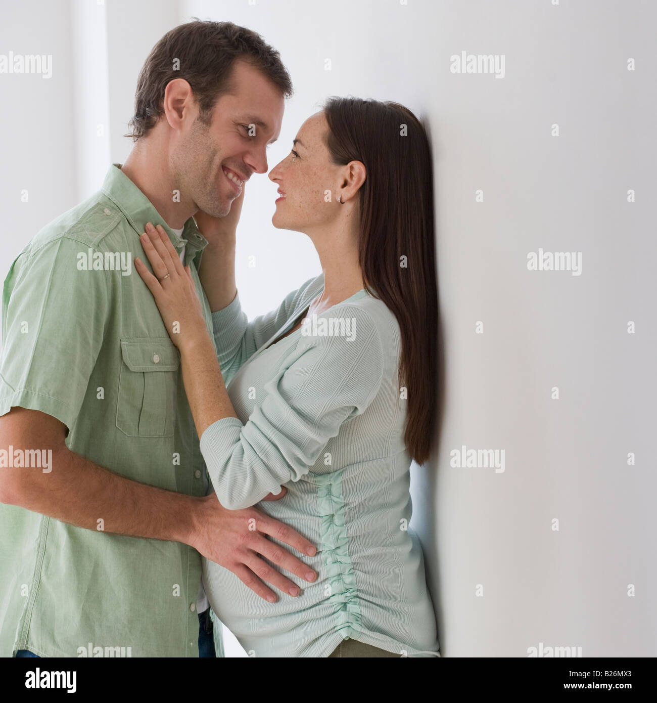 Pregnant Hispanic couple hugging Stock Photo - Alamy