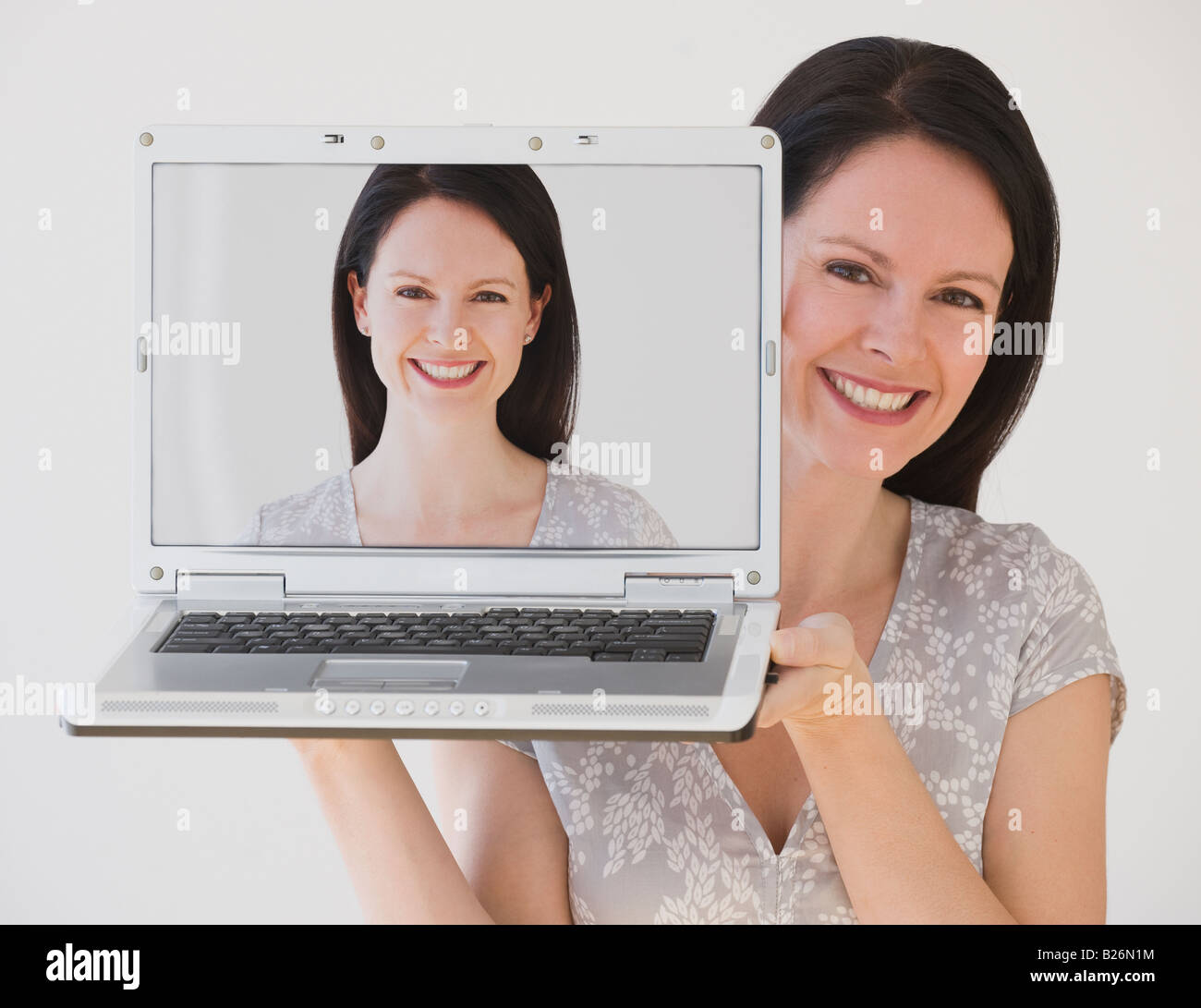 Woman holding laptop next to face Stock Photo - Alamy