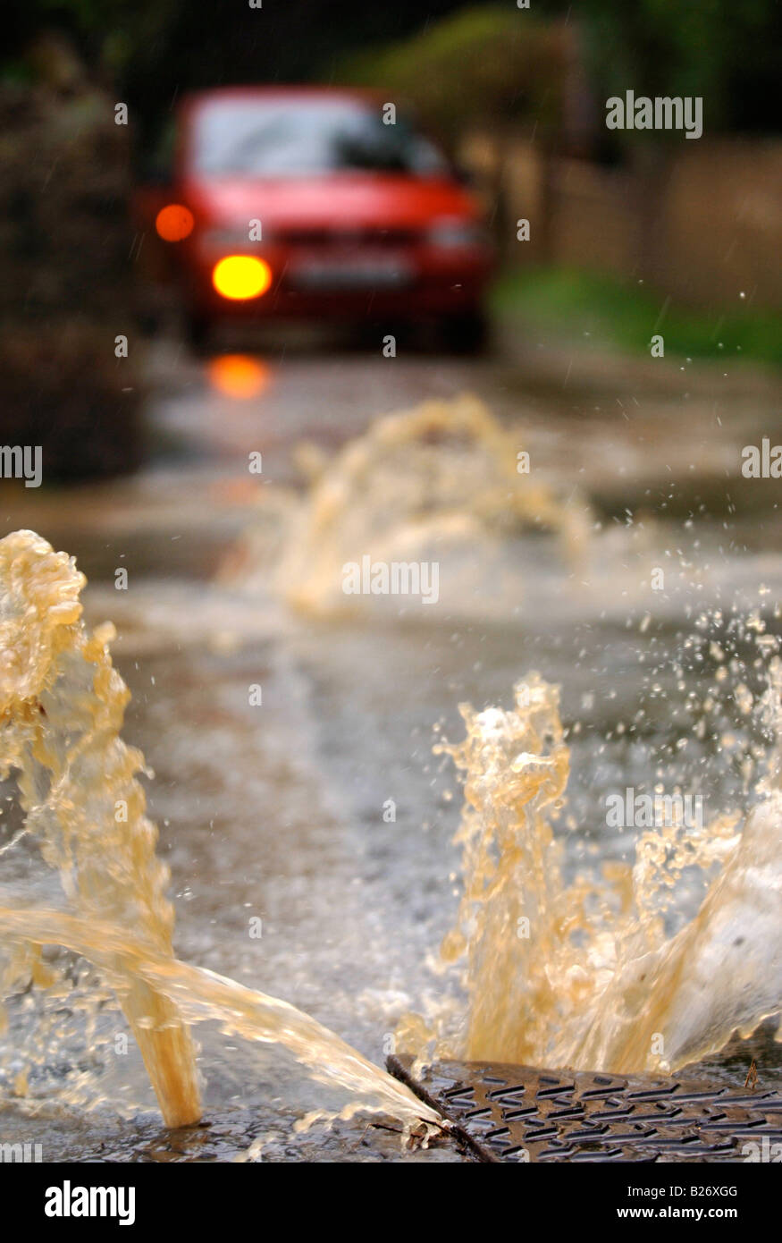 RAIN WATER SPURTS OUT OF DRAINS IN A RESIDENTIAL STREET DURING THE ...