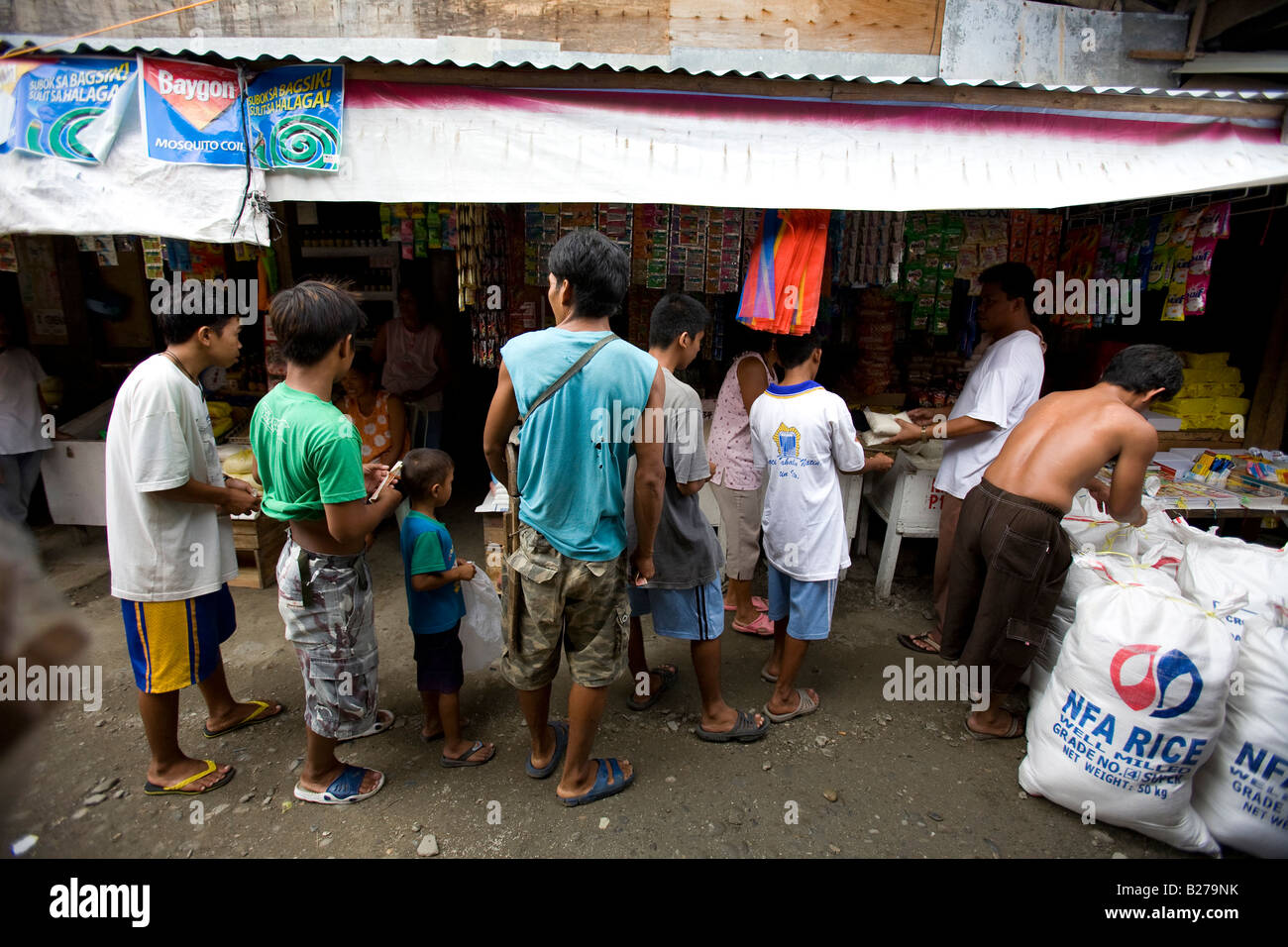 Filipinos wait in line for their weekly allowance of NFA rice at the ...