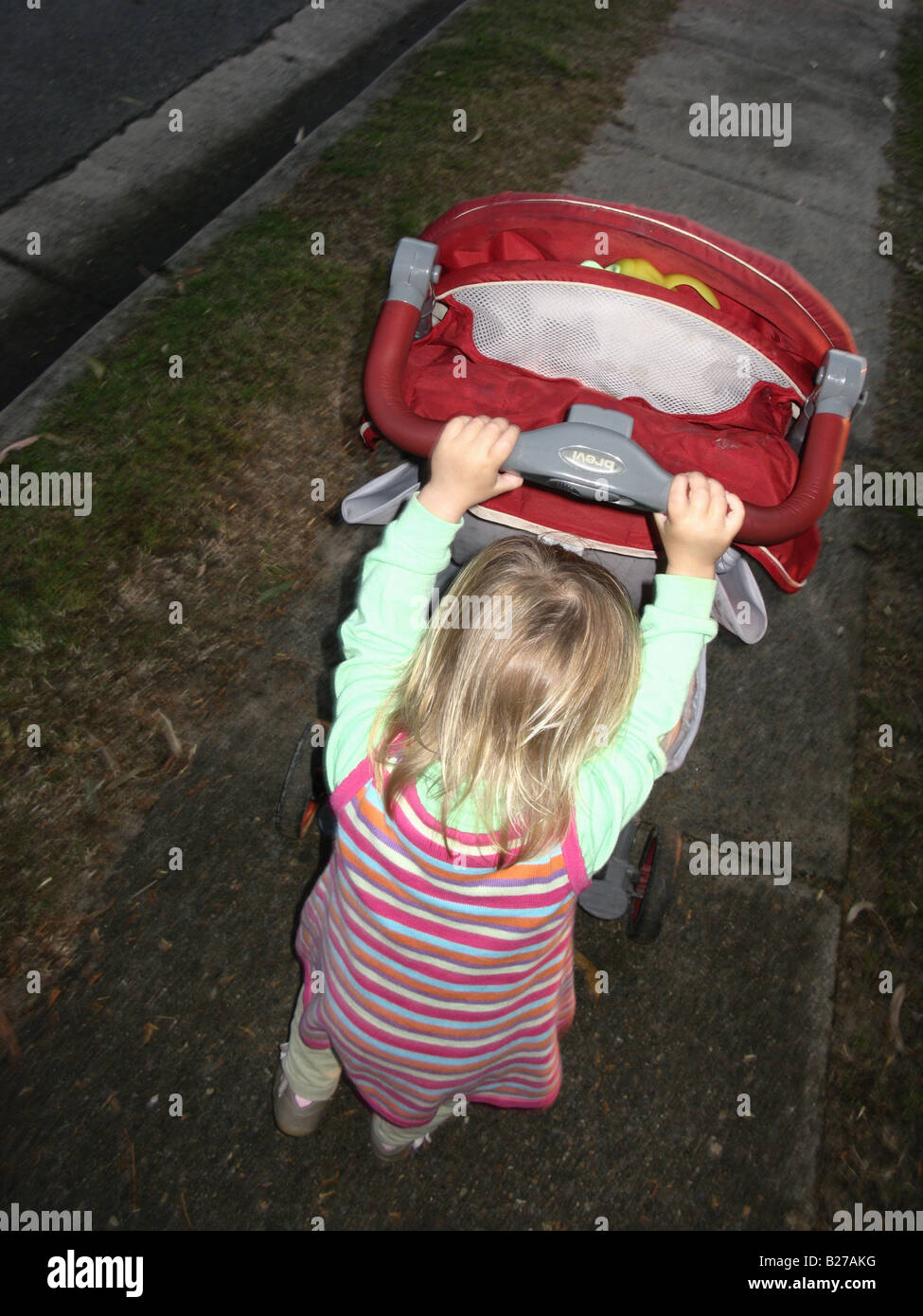 Child girl pushing her stroller on a path Stock Photo - Alamy