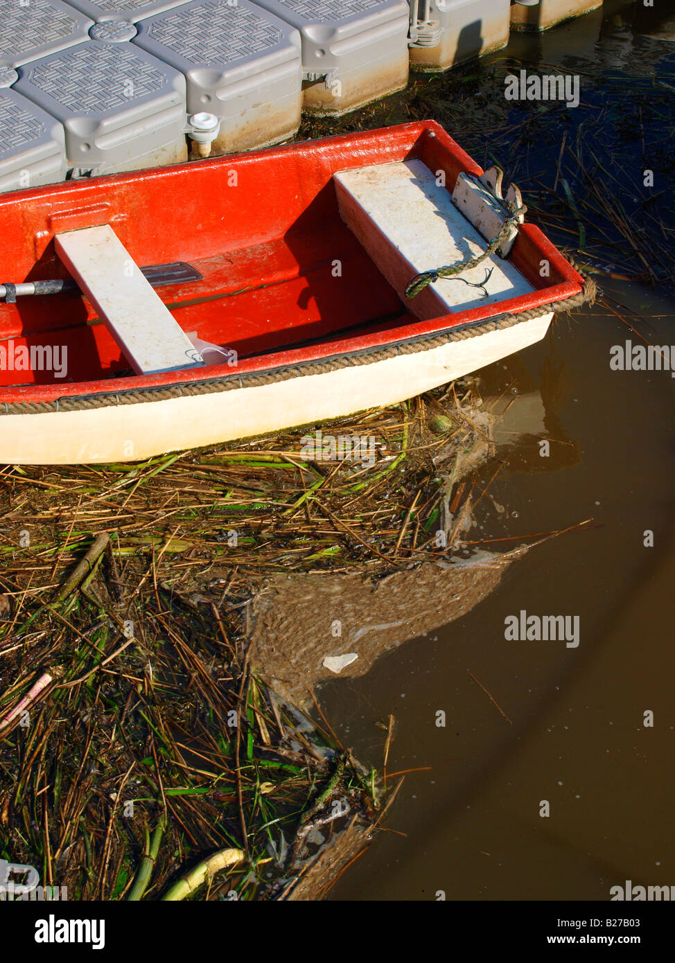 A harbouside dinghy surrounded by floating debri Stock Photo - Alamy