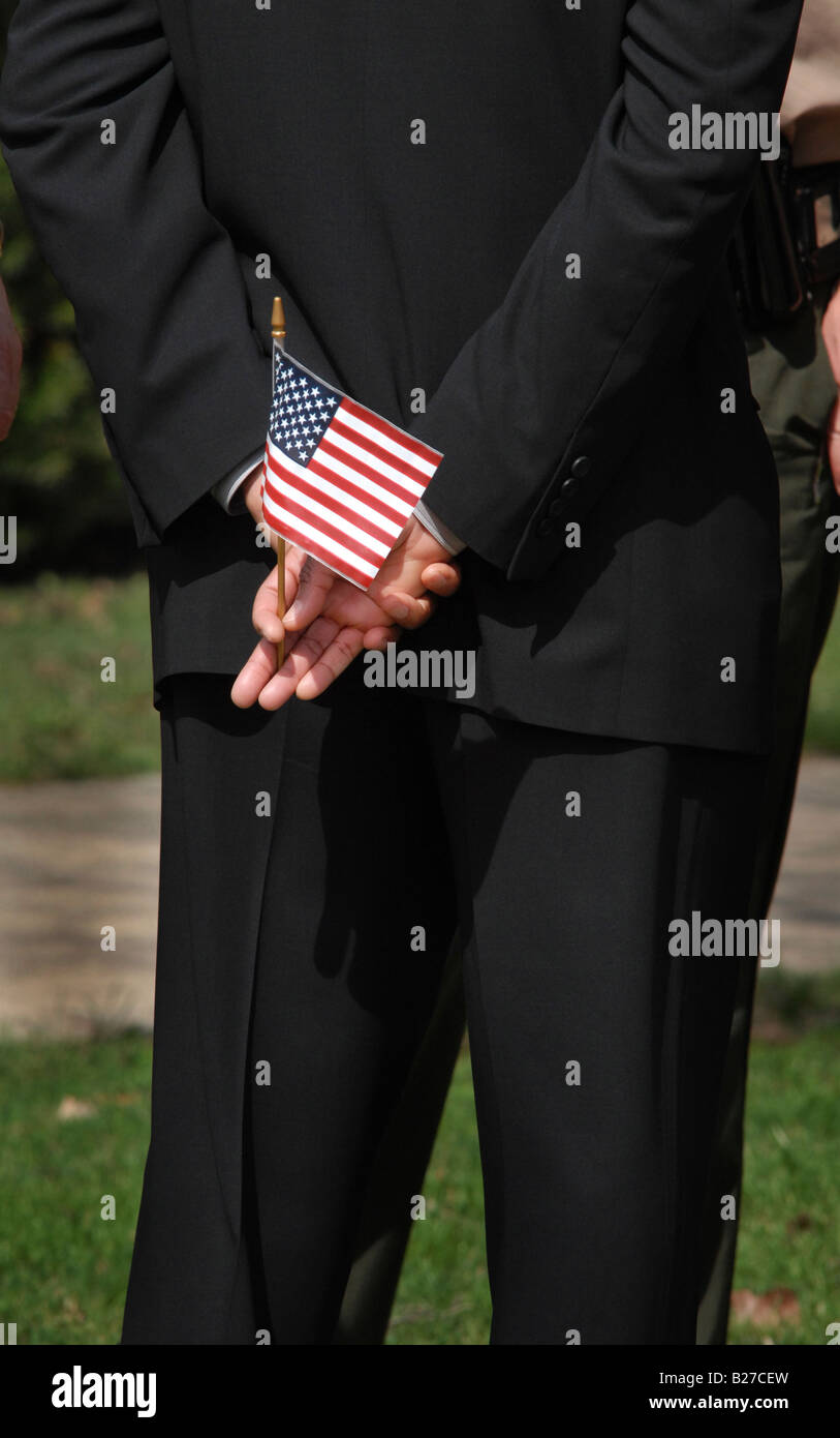 A well dressed man holds a small American flag behind his back Stock ...