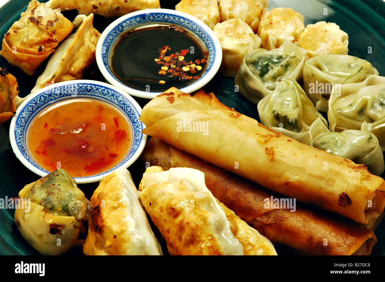 Plate of dim sum egg rolls shumai and pot stickers with dipping sauce ...