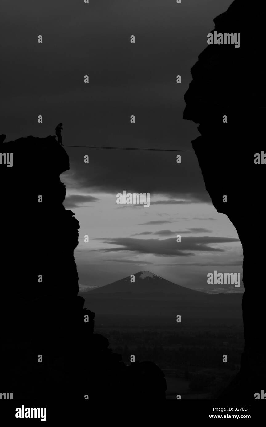 A solitary figure steps onto a rope high above the ground with a valley ...