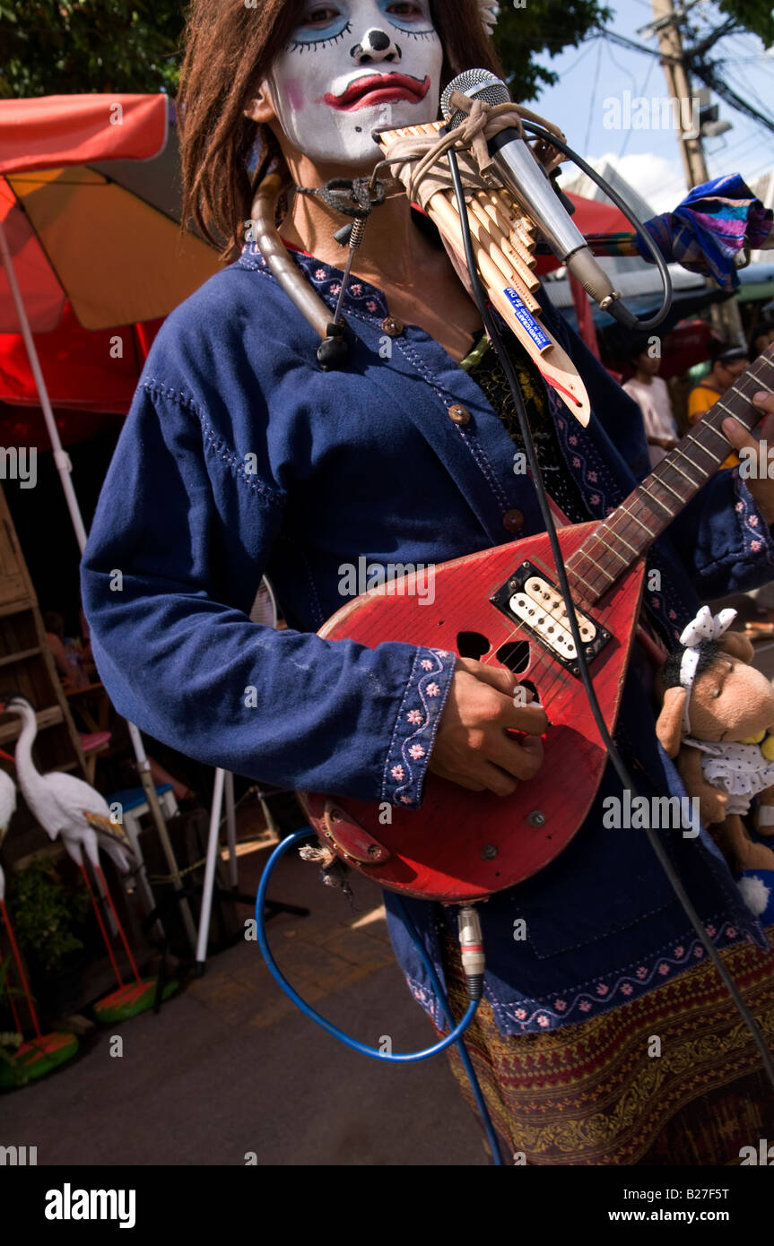 A colorful clown sings a song to the crowd in Chatuchak market, Bangkok ...