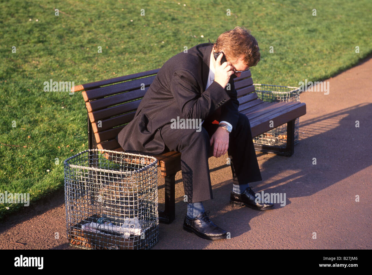 a young man using a mobile phone cell phone on a park bench Stock Photo ...
