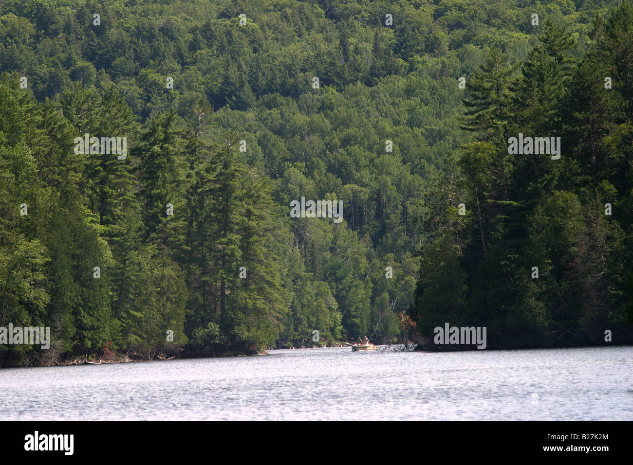 A boat navigates between two islands in a lake in the Gatineau Hills ...