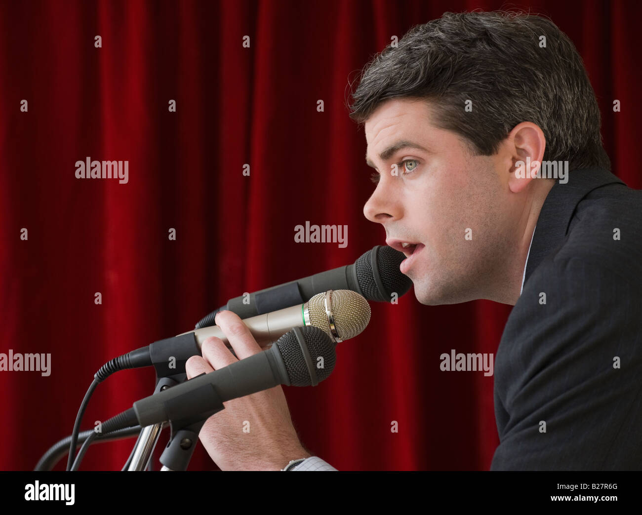 Businessman speaking into microphone Stock Photo - Alamy